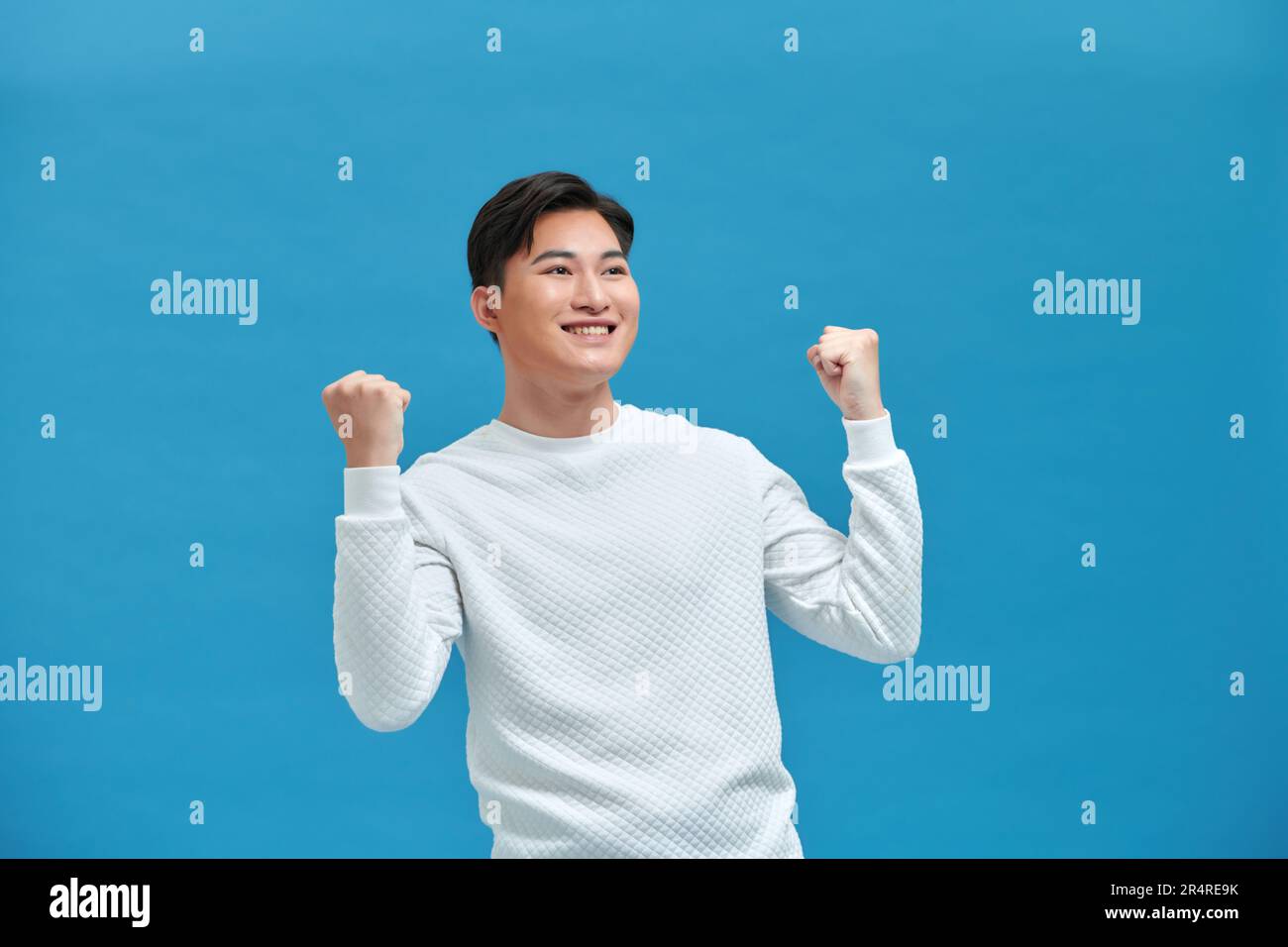 Cheerful excited man standing isolated over blue background ...