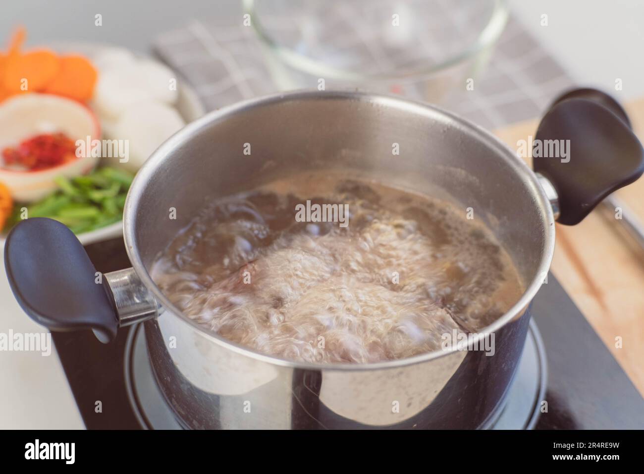Homemade bouillon recipe. Chef's hands preparing pork rib stock (broth ...