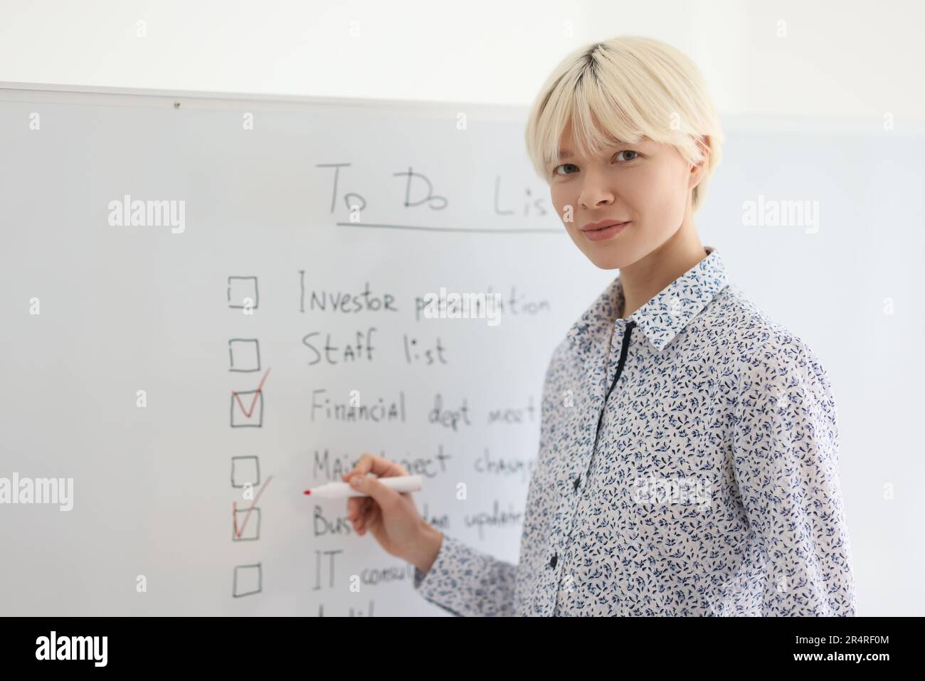 Businesswoman marks completed tasks from list on whiteboard Stock Photo ...