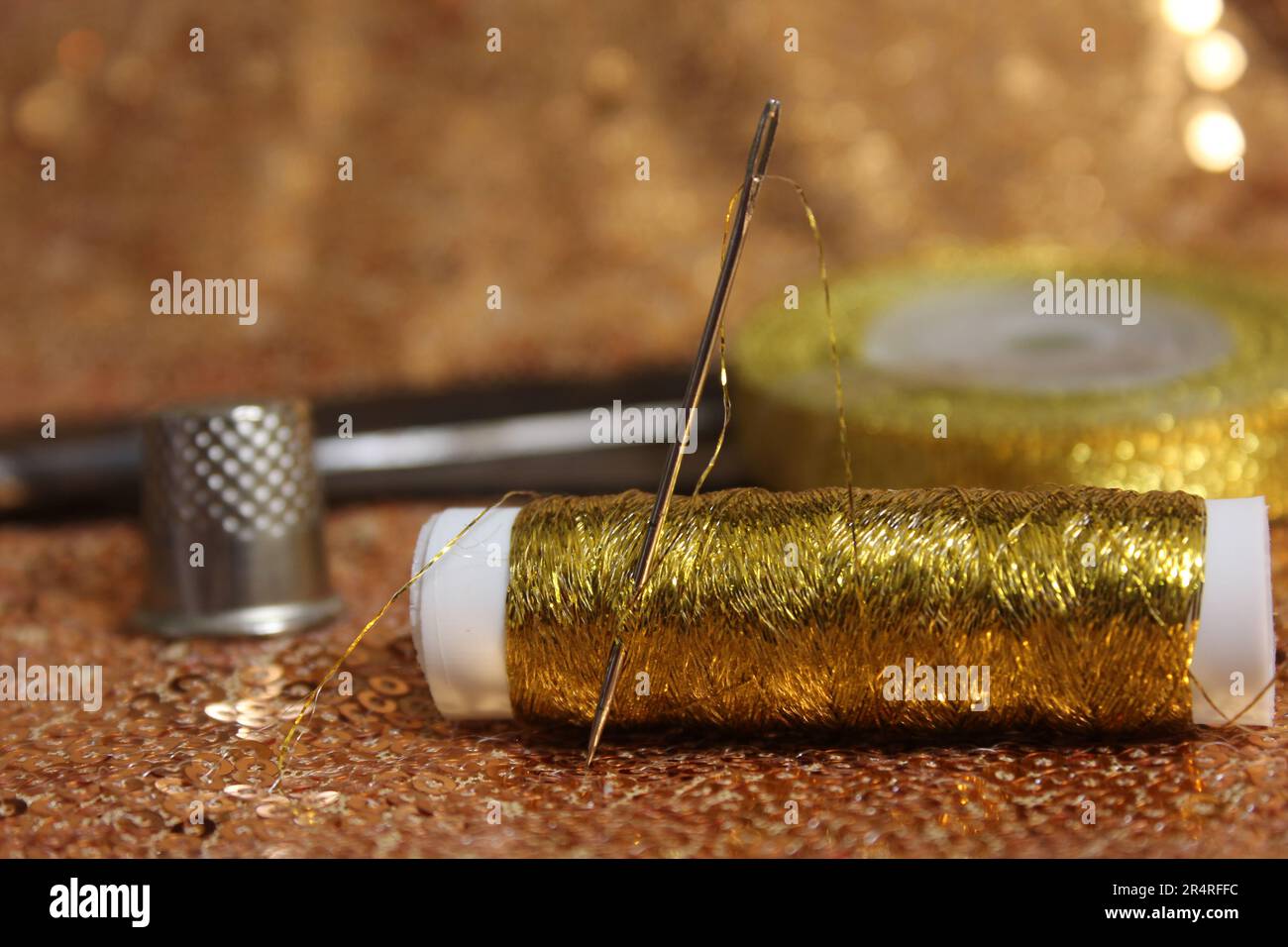 Gold Sequins on Fabric With Spool of Gold Thread and Thimble Stock ...
