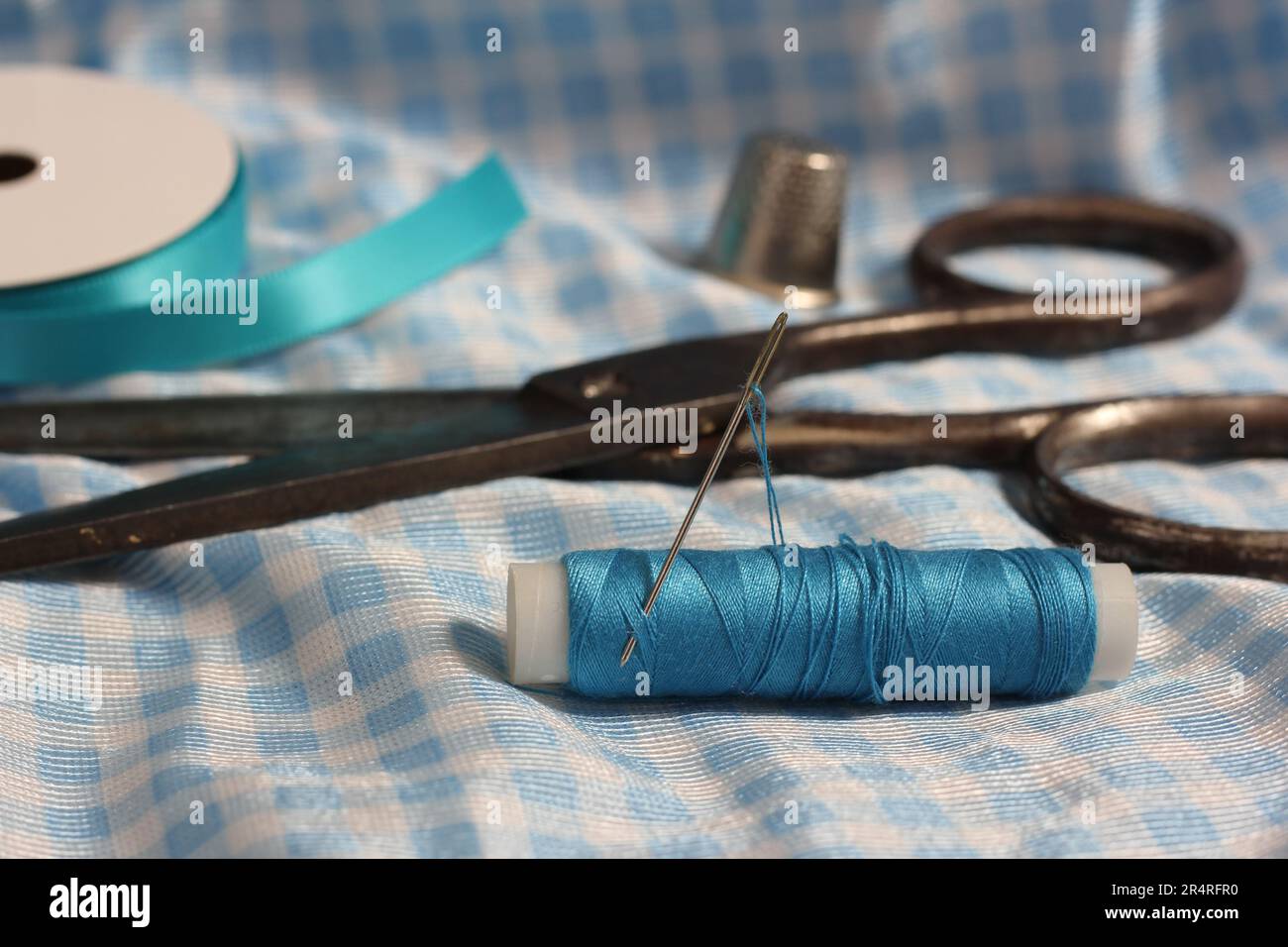 Spool of Blue Thread, Thimble and Needle on Vintage Blue and White ...
