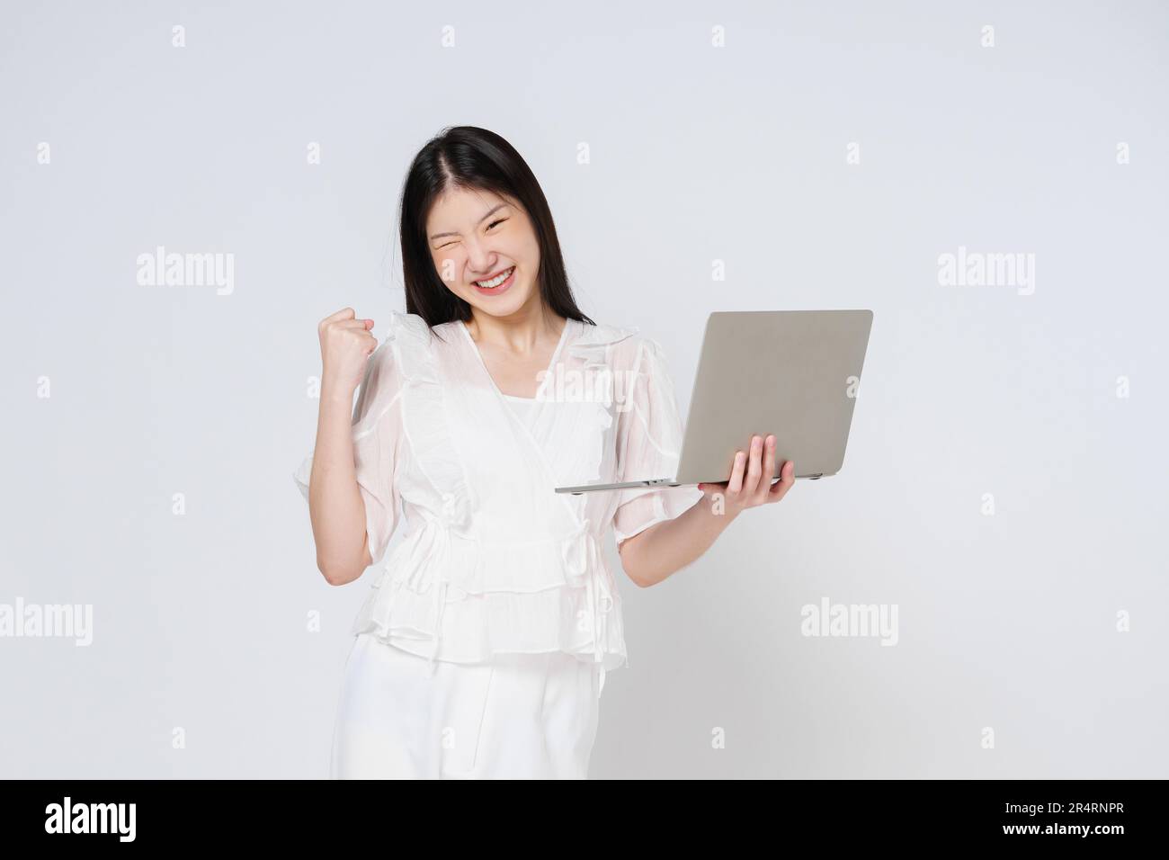 Excited young woman holding laptop computer and celebrating success ...