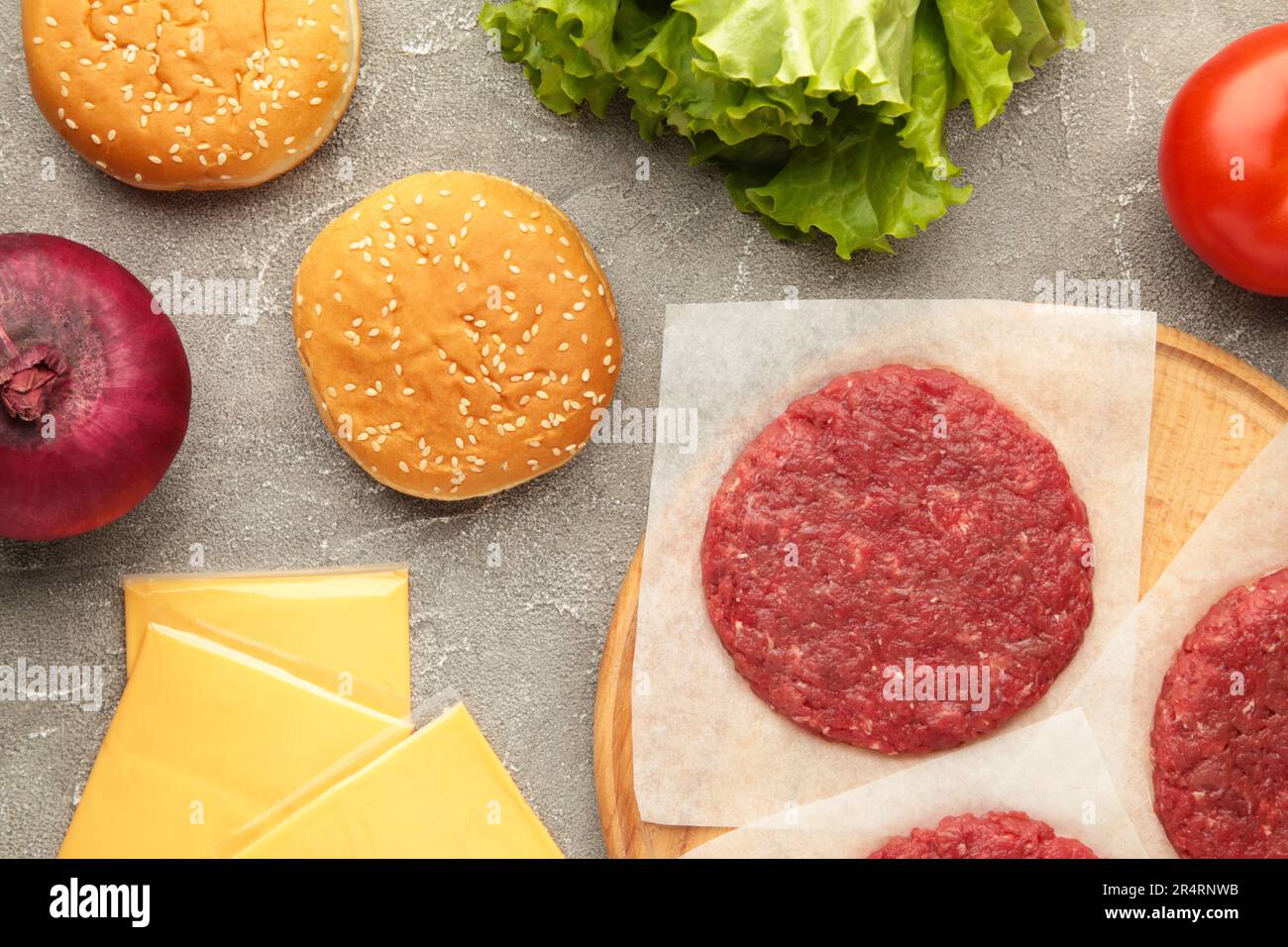 Raw Ground beef meat steak cutlets and burger ingredients on grey table ...