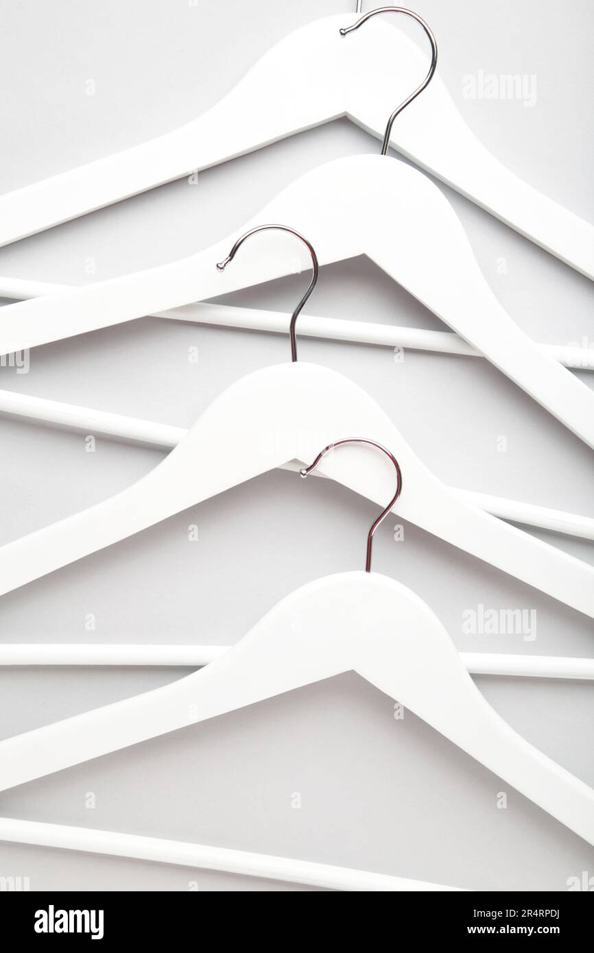 Many wooden white hangers on white wall background. Store concept ...