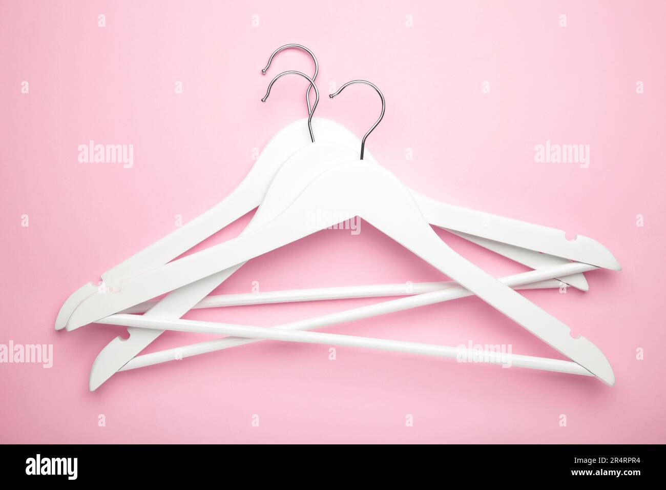 Many wooden white hangers on pink background. Store concept, empty ...
