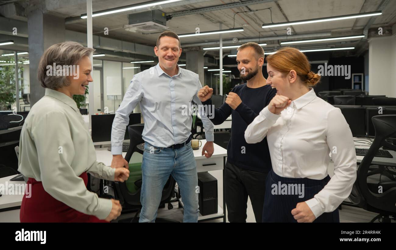Four colleagues give the low five in the office Stock Photo - Alamy