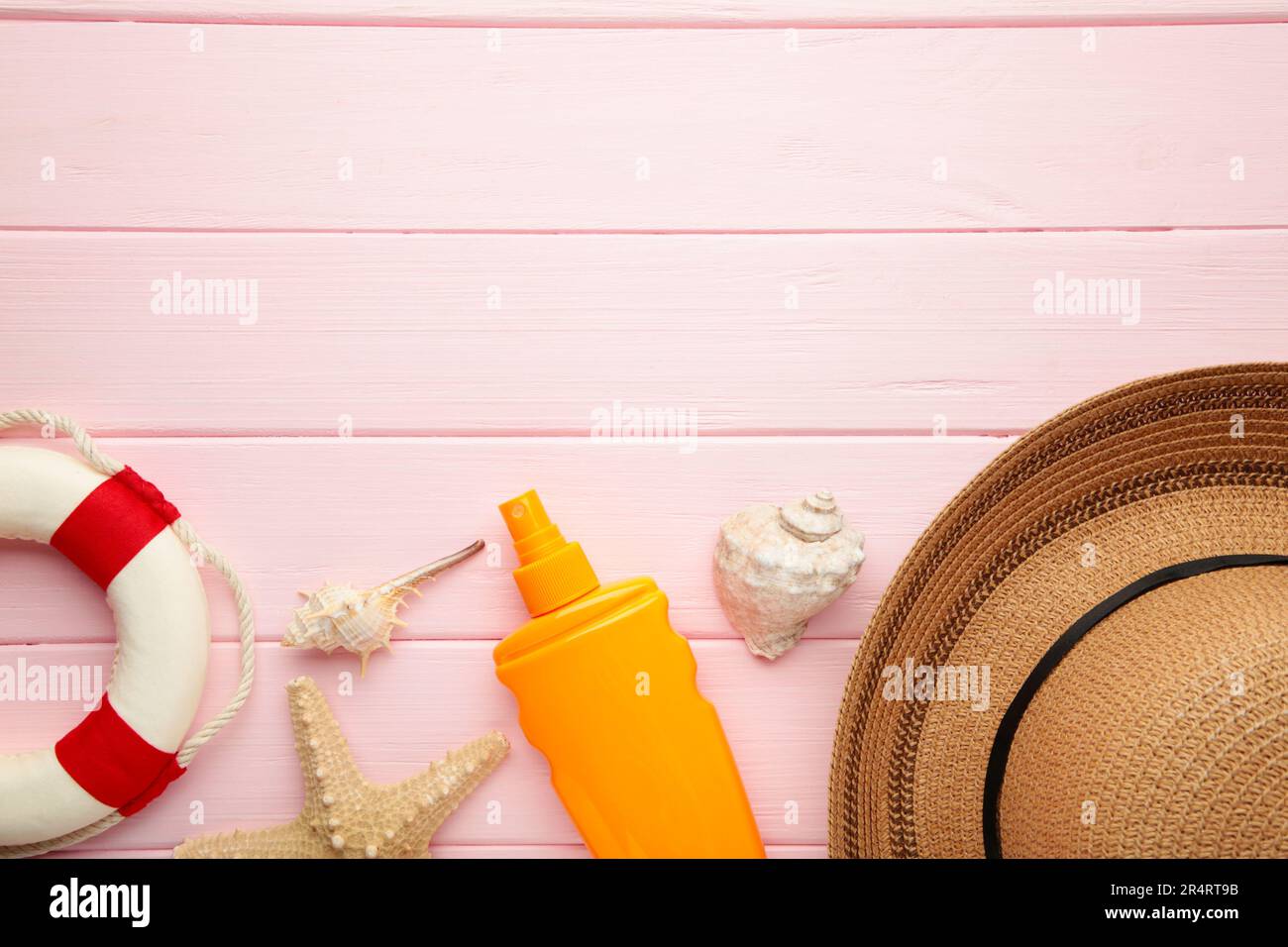 Sunscreen bottle with hat, glasses and other accessories on pink ...
