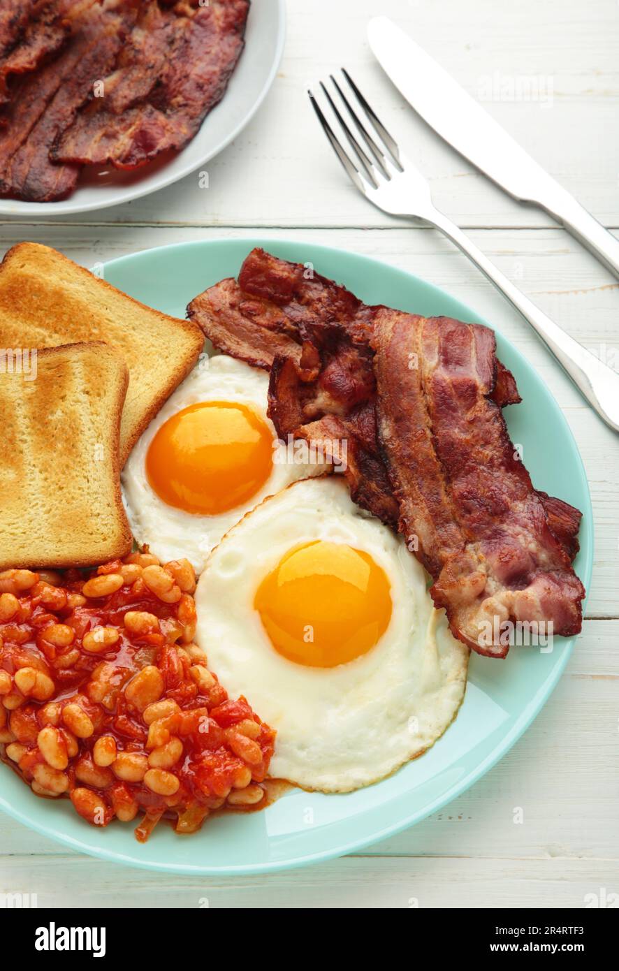 Traditional full English breakfast - fried eggs, beans, bacon and toast ...