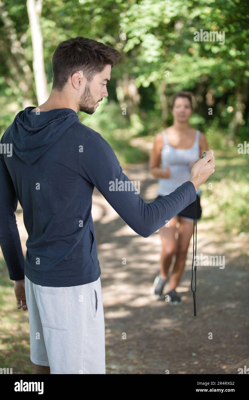 Female runner approaching man holding stopwatch Stock Photo - Alamy