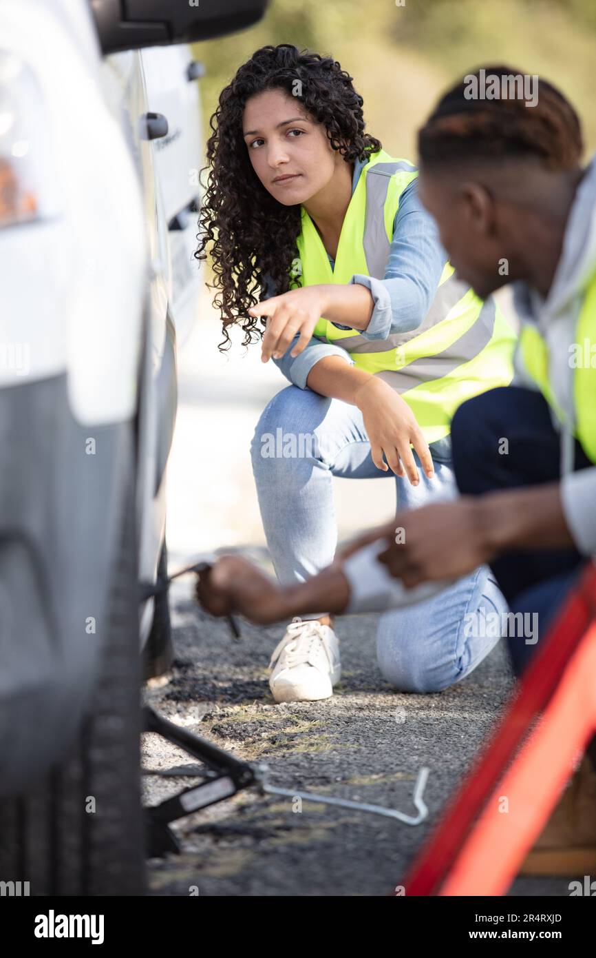 couple wearing reflective-vests repairing car puncture Stock Photo - Alamy