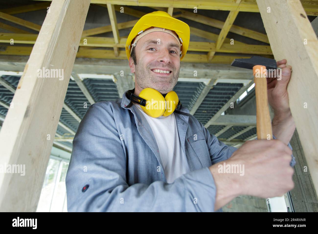 happy man builder hammer wood structure indoors Stock Photo - Alamy