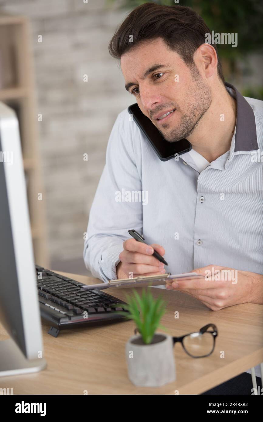 young man in formalwear making notes while talking on phone Stock Photo ...