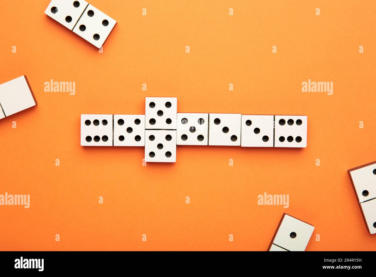 Playing dominoes on a orange table. Domino effect. Top view Stock Photo ...