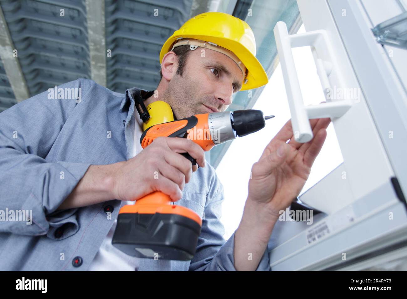 male worker is drill a window Stock Photo - Alamy
