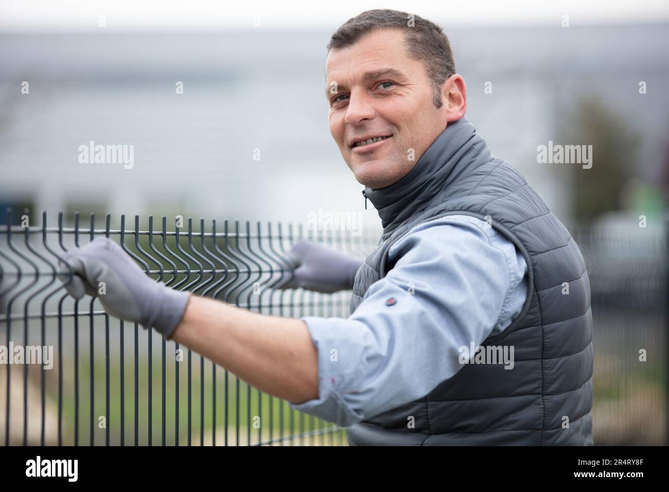 worker installing welded metal mesh fence Stock Photo - Alamy