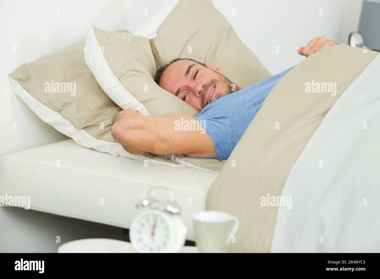 smiling man stretching in bed Stock Photo - Alamy