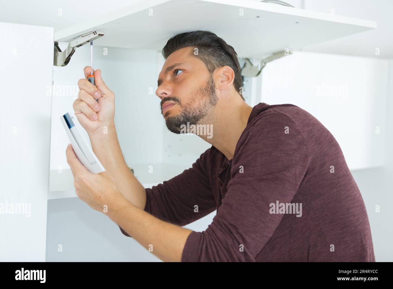 man following instructions to assemble kitchen cupboard Stock Photo - Alamy