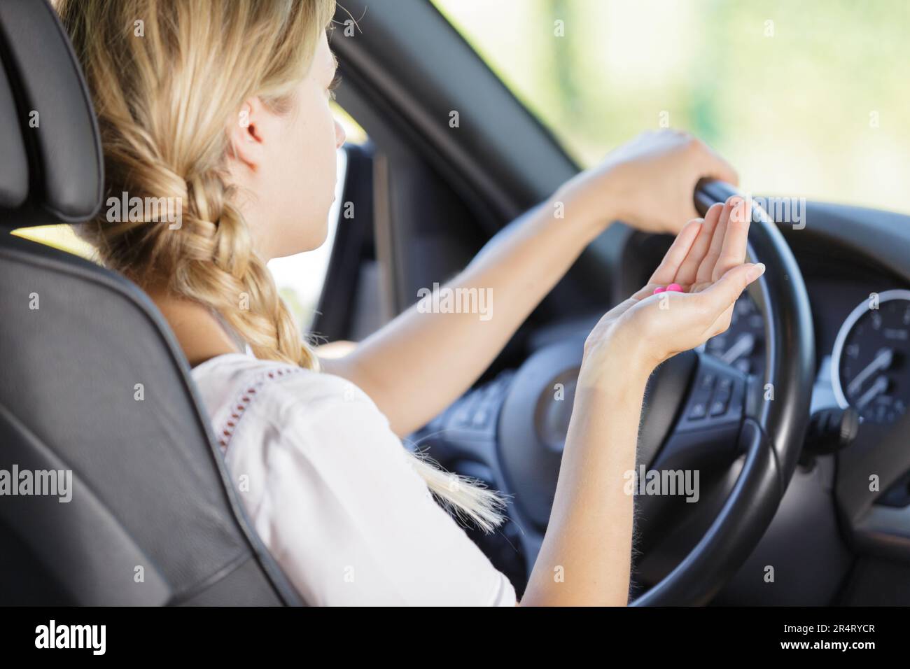 women taking pills inside his car while driving Stock Photo - Alamy