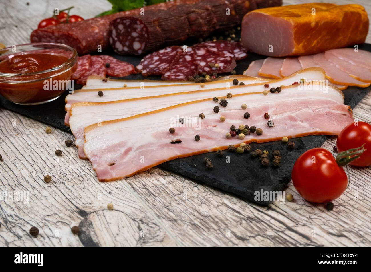 Antipasti different types of sausages and lard on a graphite board .Top ...