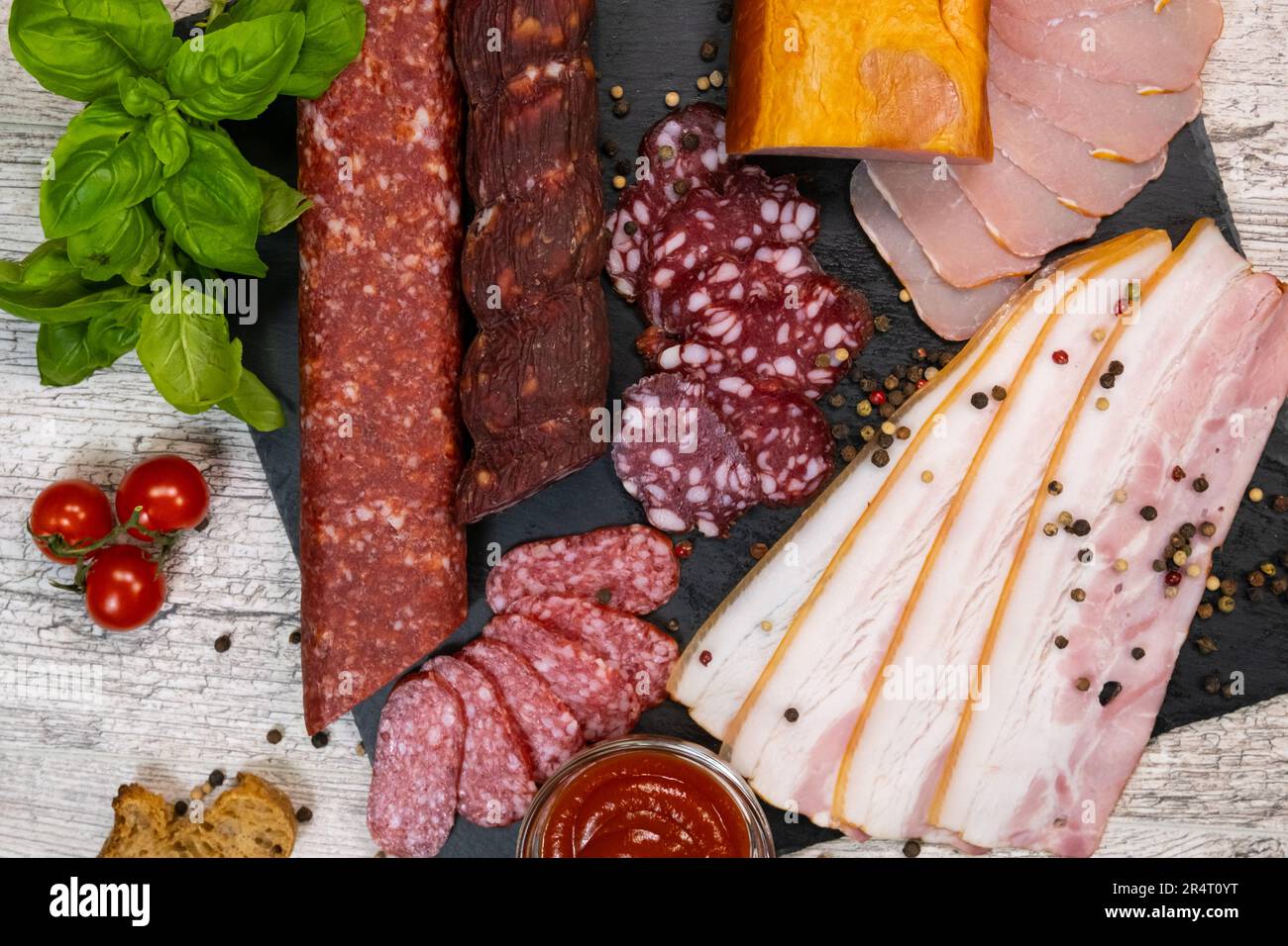 Antipasti different types of sausages and lard on a graphite board .Top ...