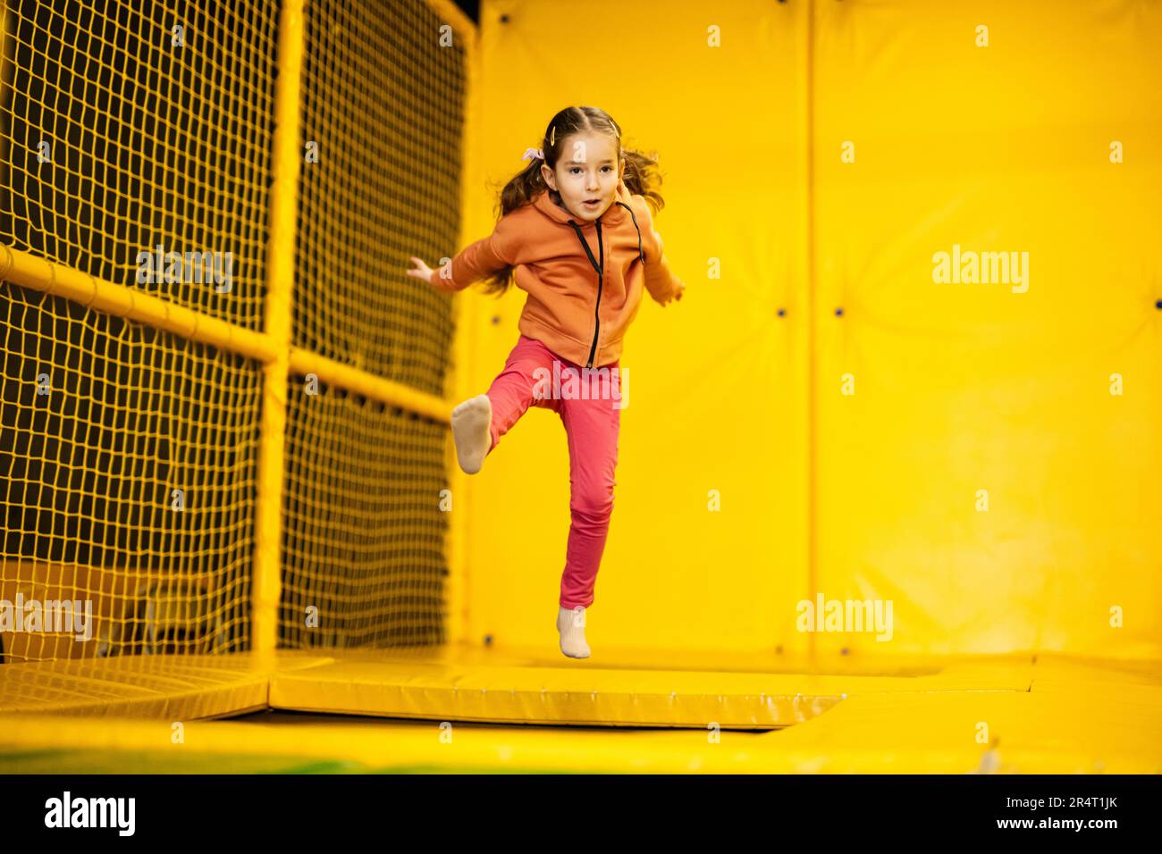 Little girl kid jumping on trampoline at yellow playground park. Child ...