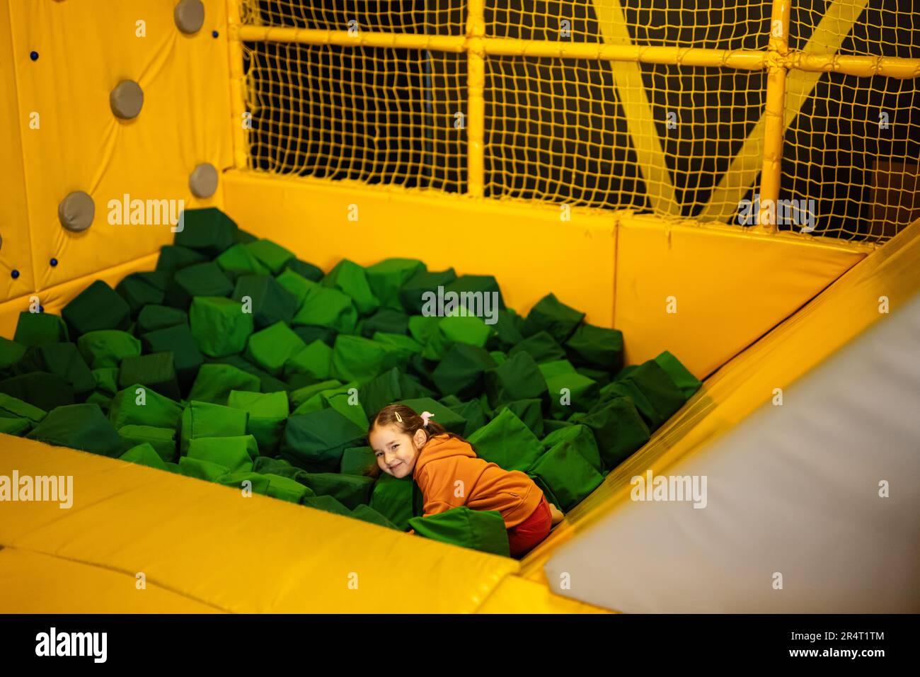 Little girl kid slide to green soft cubes at yellow playground park ...