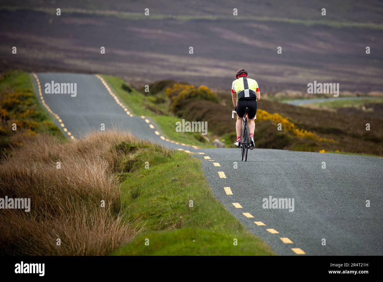 Rear view of a lone cyclist in the Wicklow Mountains on the road to ...