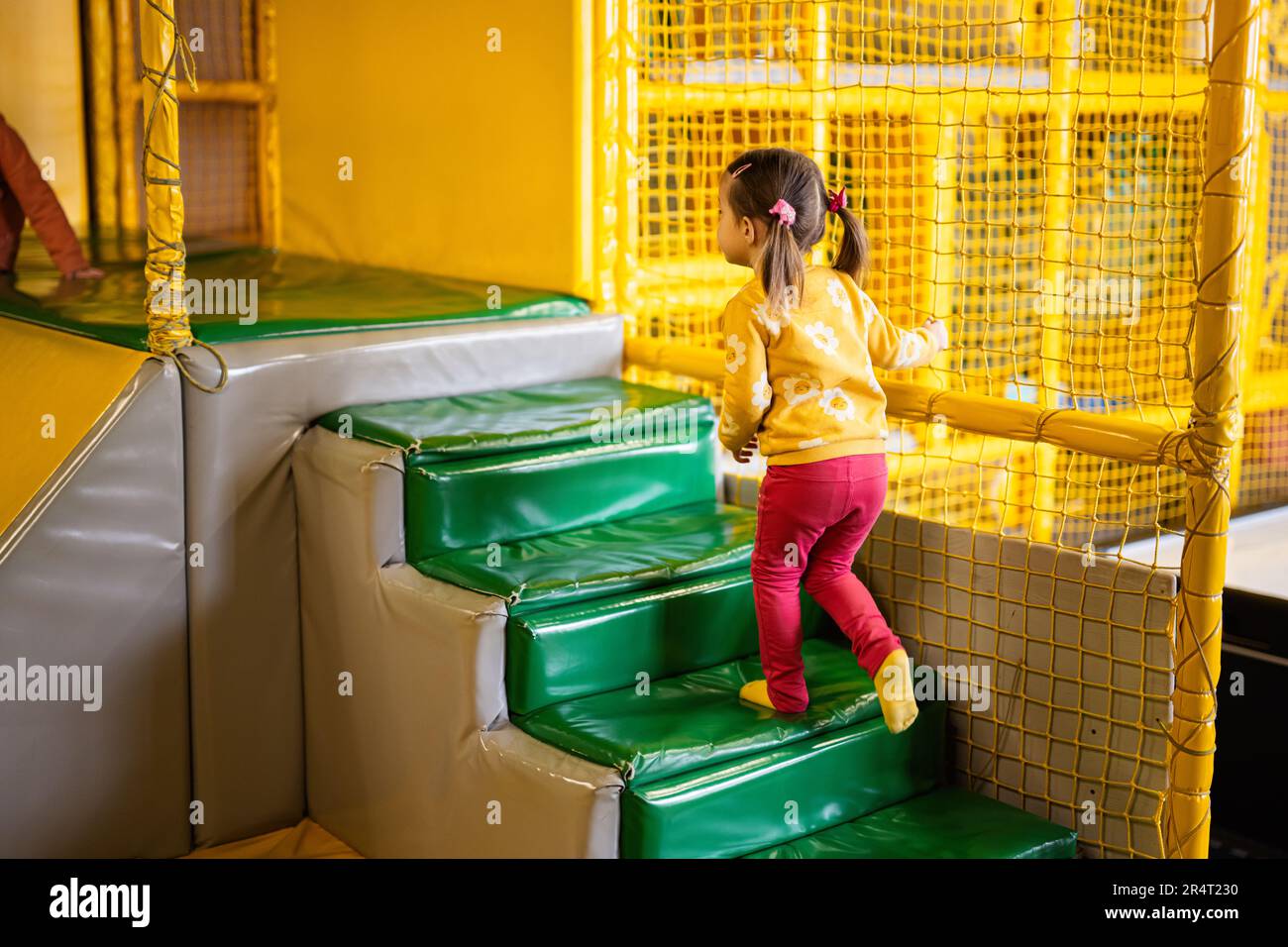 Little girl step up in stairs at yellow playground park. Child in ...