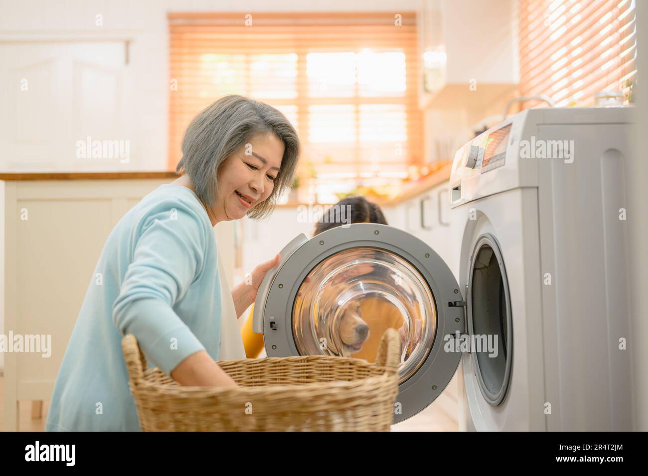 a beautiful senior woman, takes care of the laundry using a washing ...