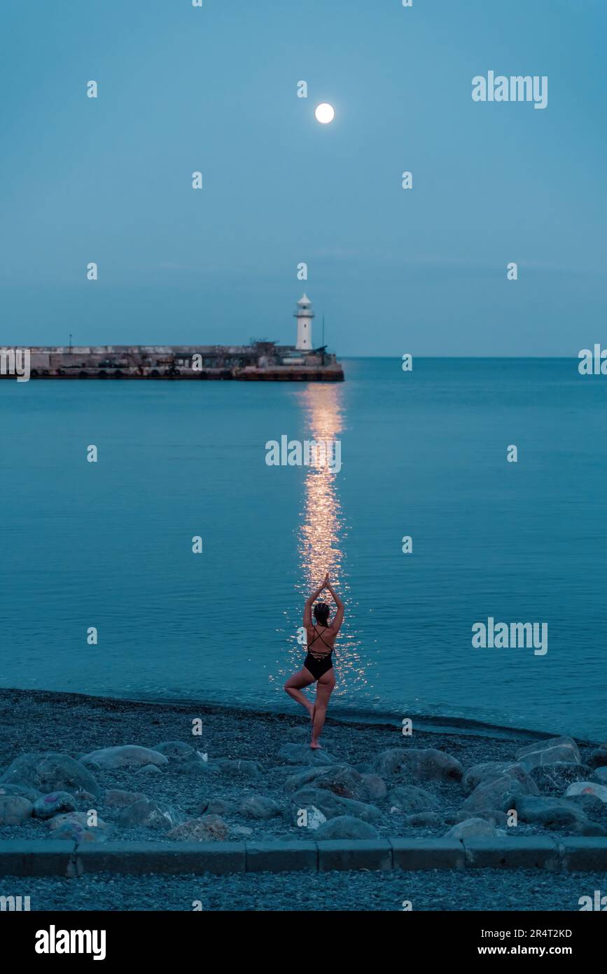Full moon rises to the lighthouse, lunar path on the sea woman Stock ...