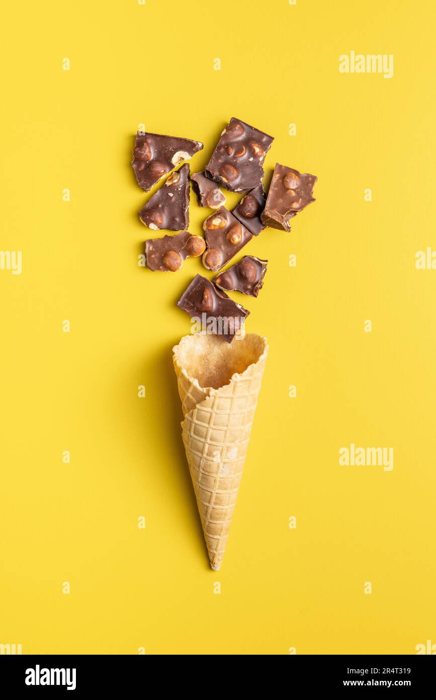 Ice cream cone and chocolate bar with nuts on the yellow background ...