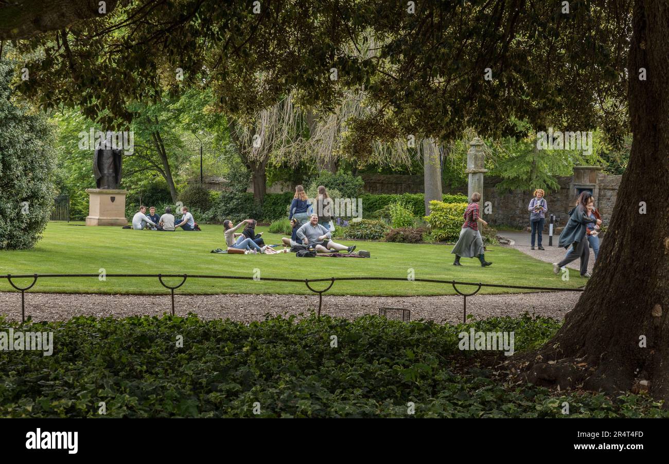 A group of students relaxing in, or walking through, the quadrangle of ...