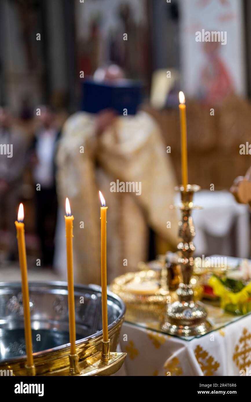 detail of candles with the orthodox parish priest celebrating mass ...