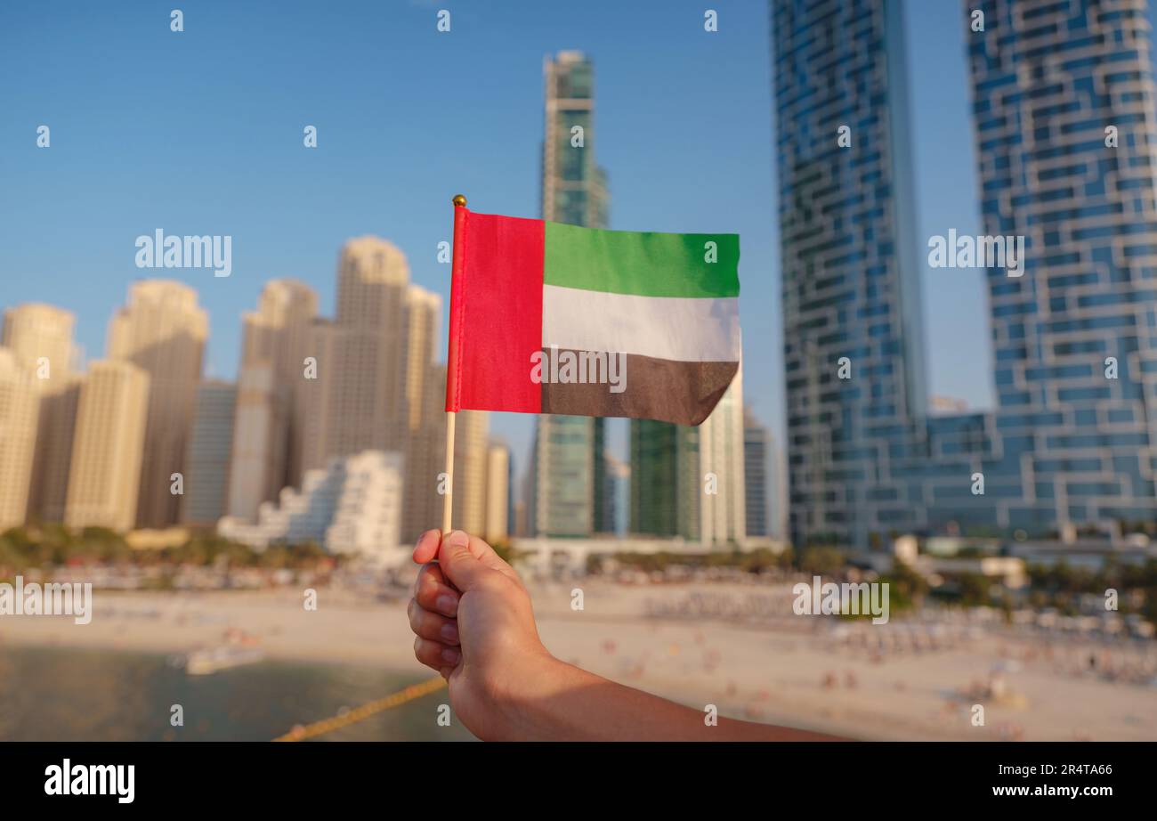 Close up of a female hand holding tiny flag of UAE against Dubai ...
