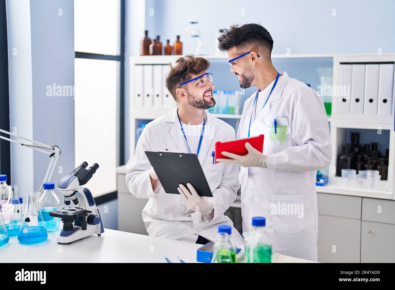 Young couple wearing scientist uniform using touchpad at laboratory ...
