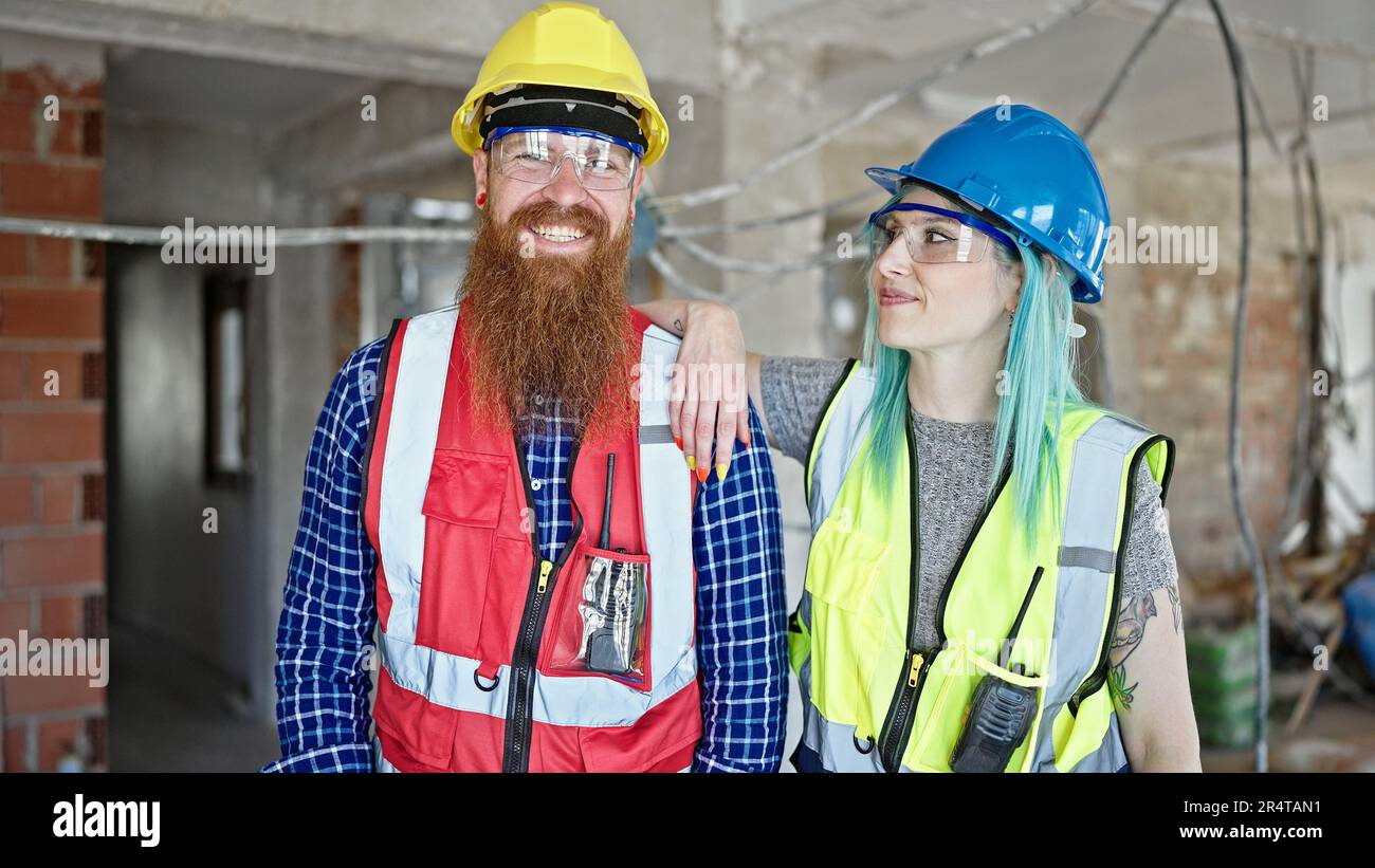 Man and woman builders smiling confident standing together at ...