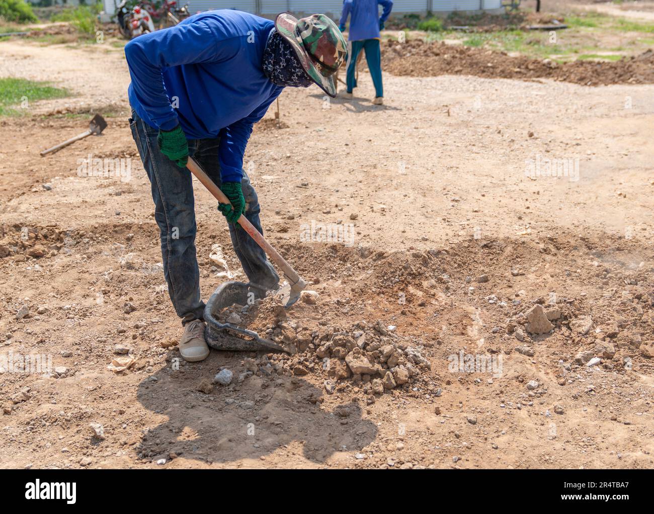 Worker digs soil with shovel on road for adjust surface before pour ...