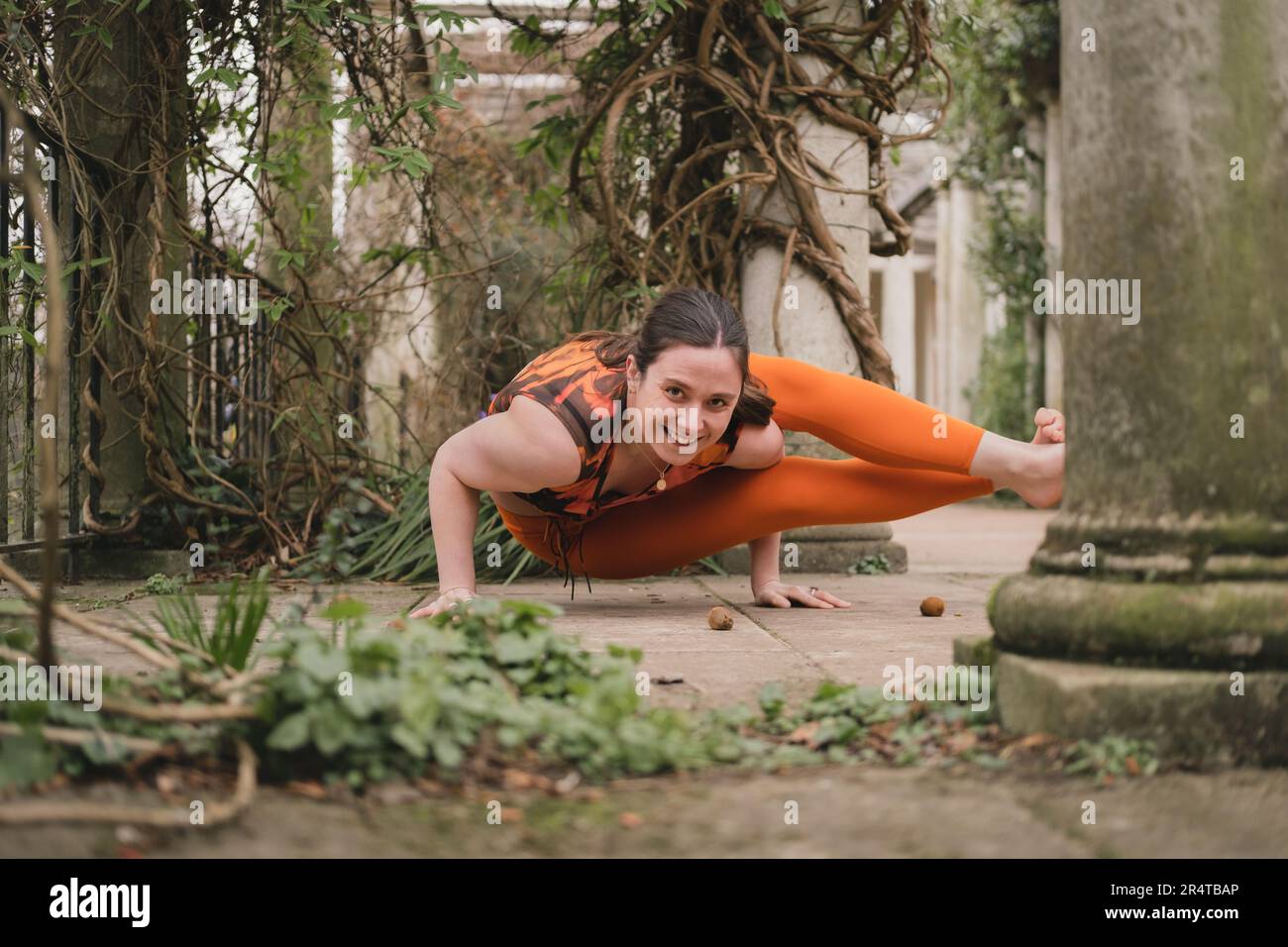 Irish female new yoga teacher doing an eight'angle pose wearing orange ...