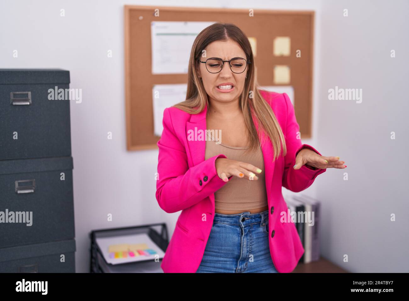 Young blonde woman standing at the office disgusted expression ...