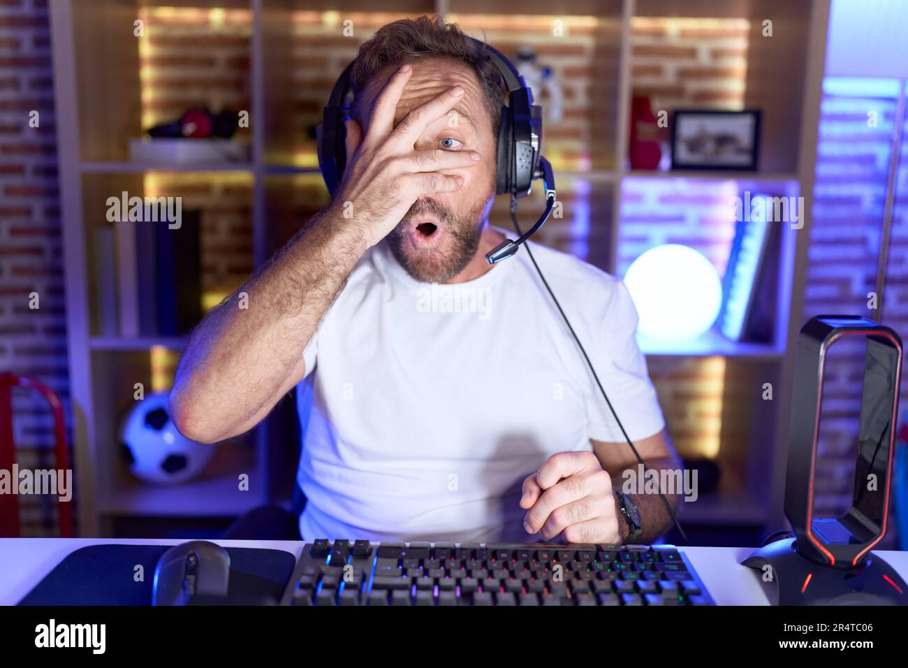 Middle age man with beard playing video games wearing headphones ...