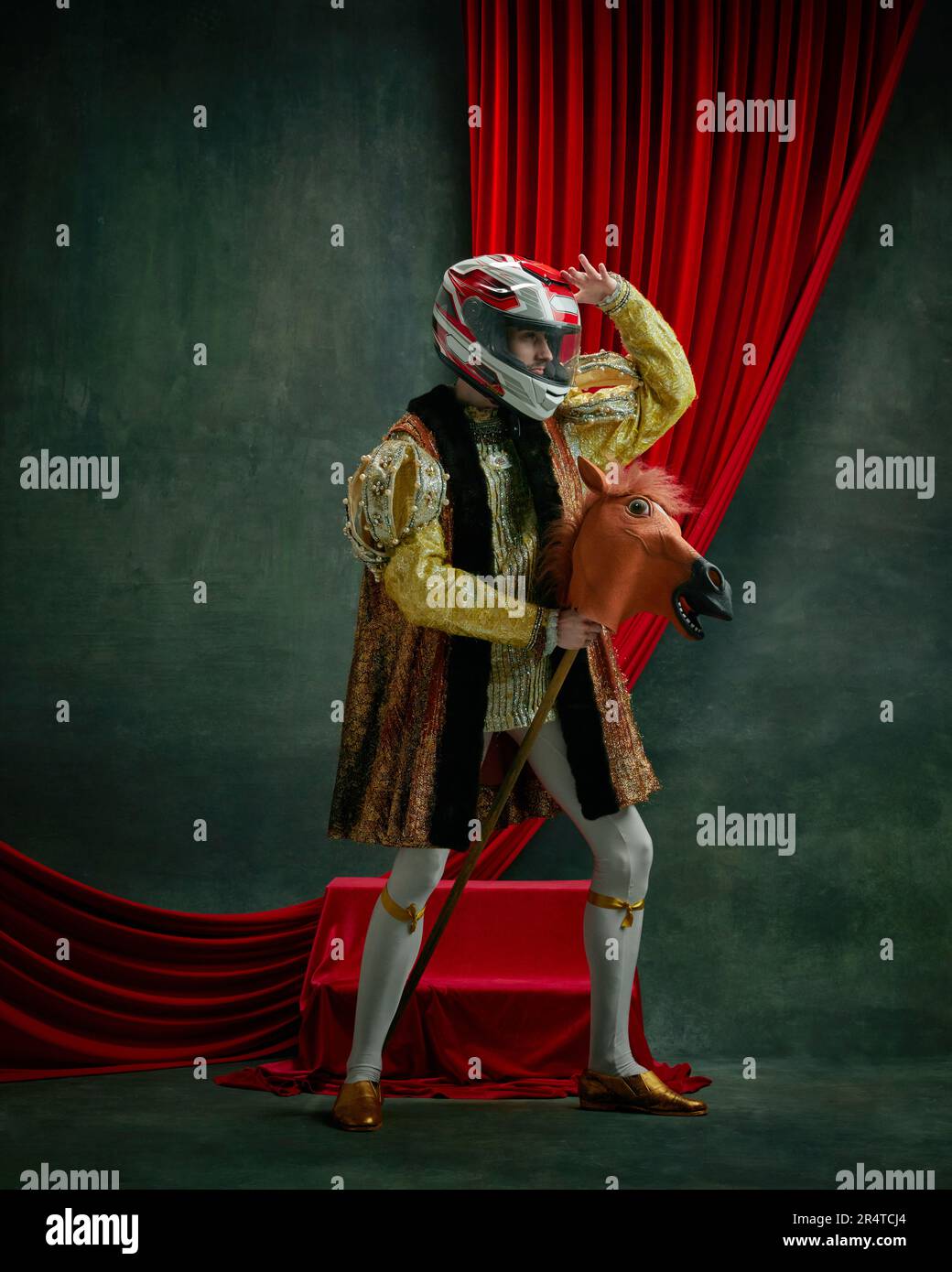 Portrait of young man, royal person in moto helmet riding toy horse ...