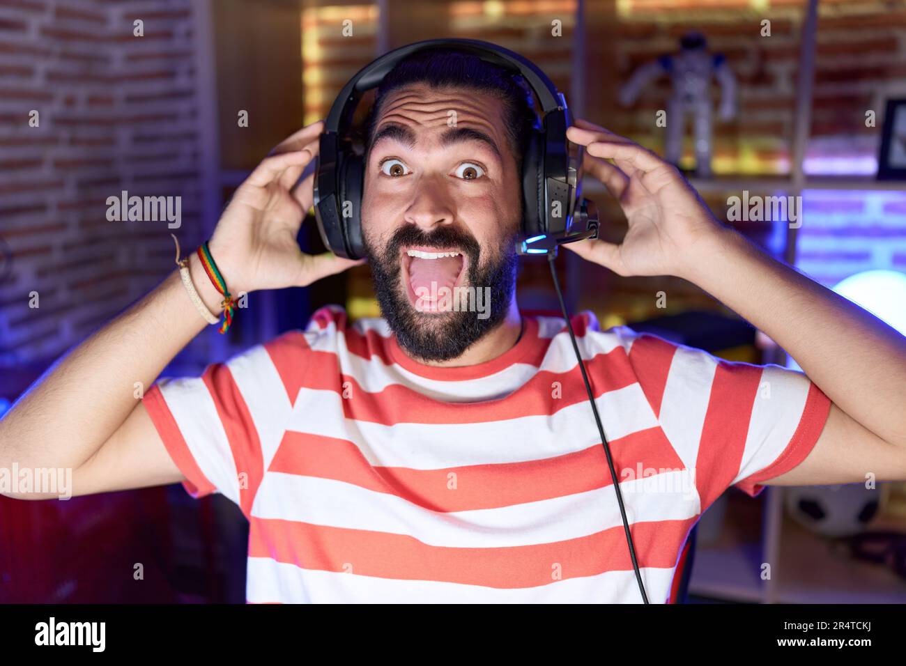 Hispanic man with beard playing video games wearing headphones ...