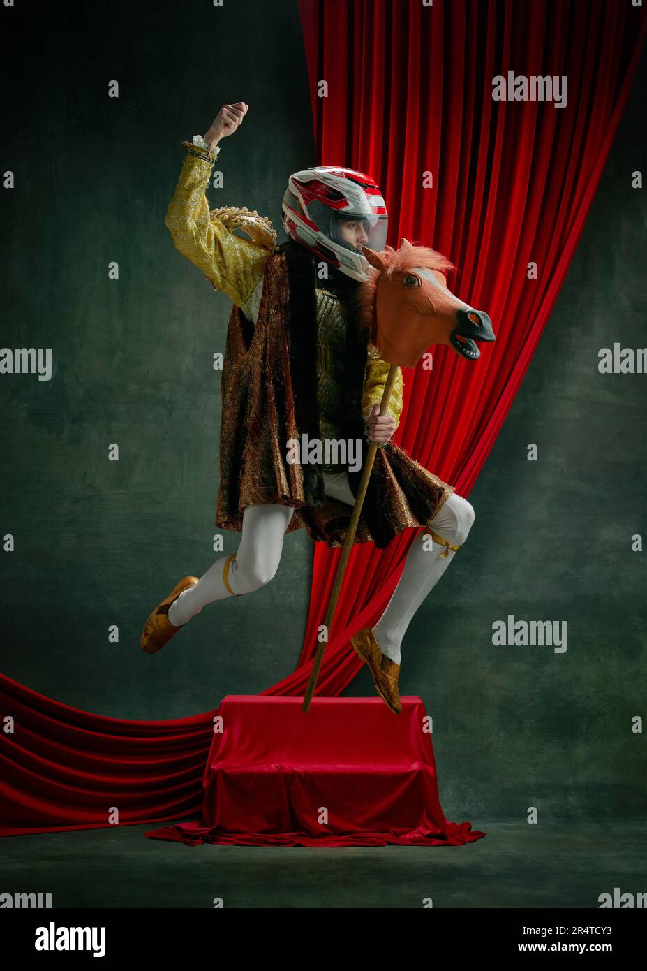 Portrait of young man, royal person in moto helmet riding toy horse ...