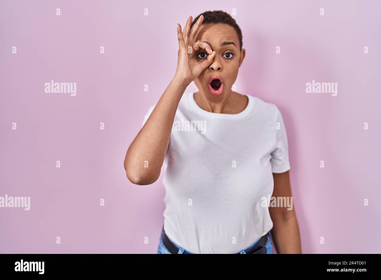 Beautiful african american woman standing over pink background doing ok ...