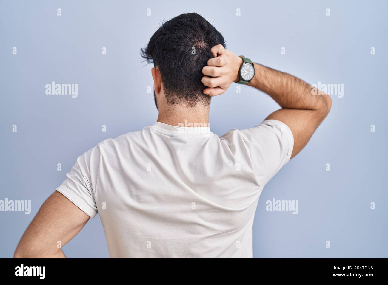 Hispanic man with beard standing over white background backwards ...