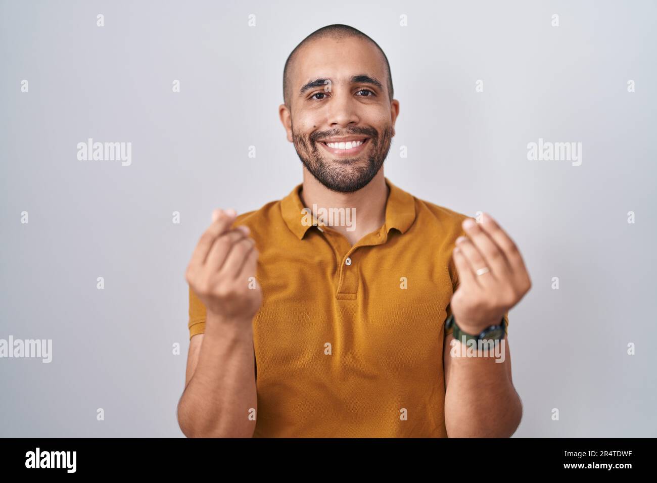 Hispanic man with beard standing over white background doing money ...