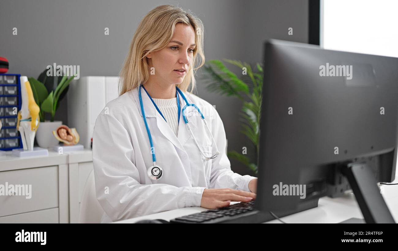 Young blonde woman doctor using computer working at clinic Stock Photo ...