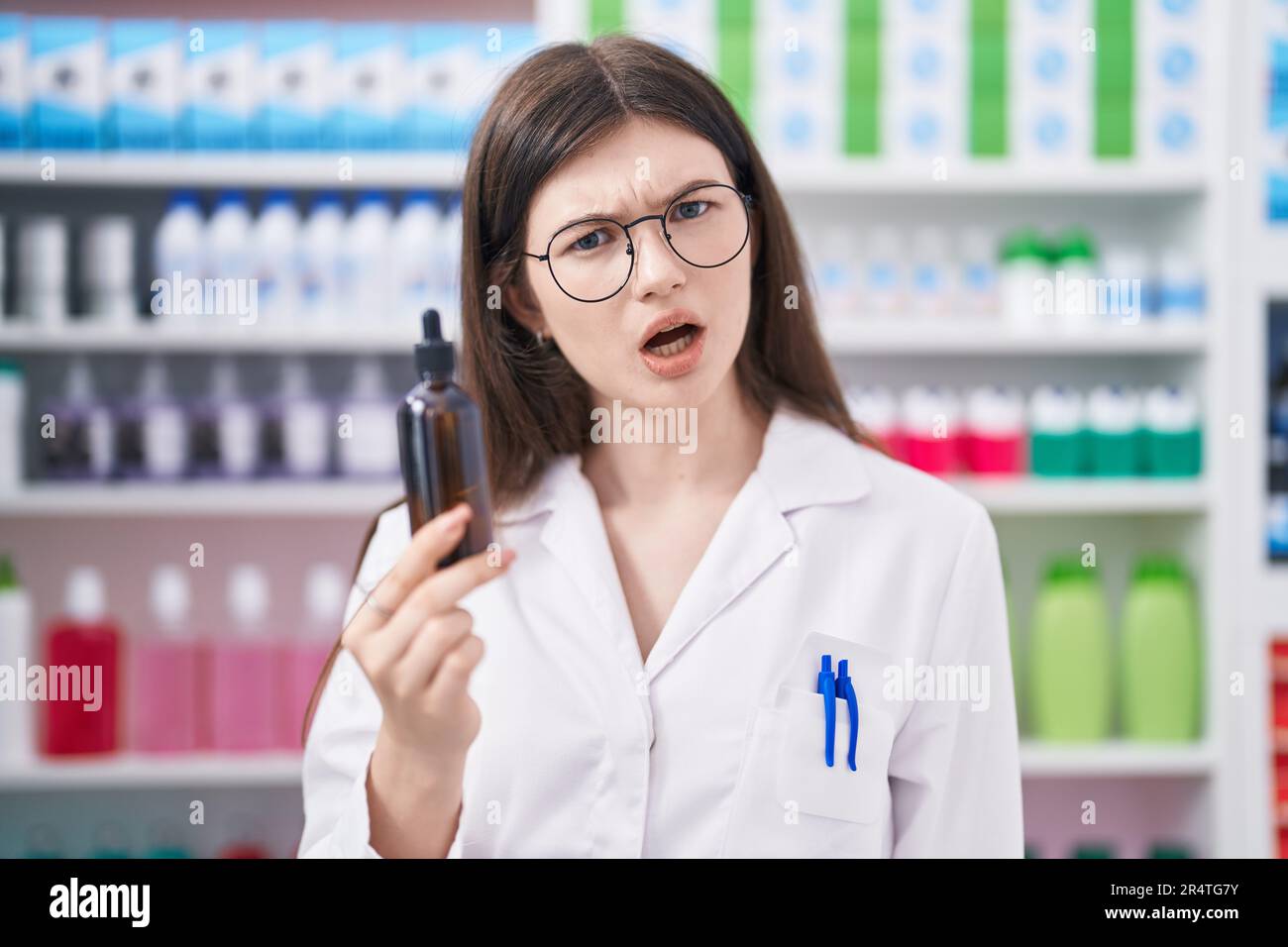 Young caucasian woman working at pharmacy drugstore holding serum ...