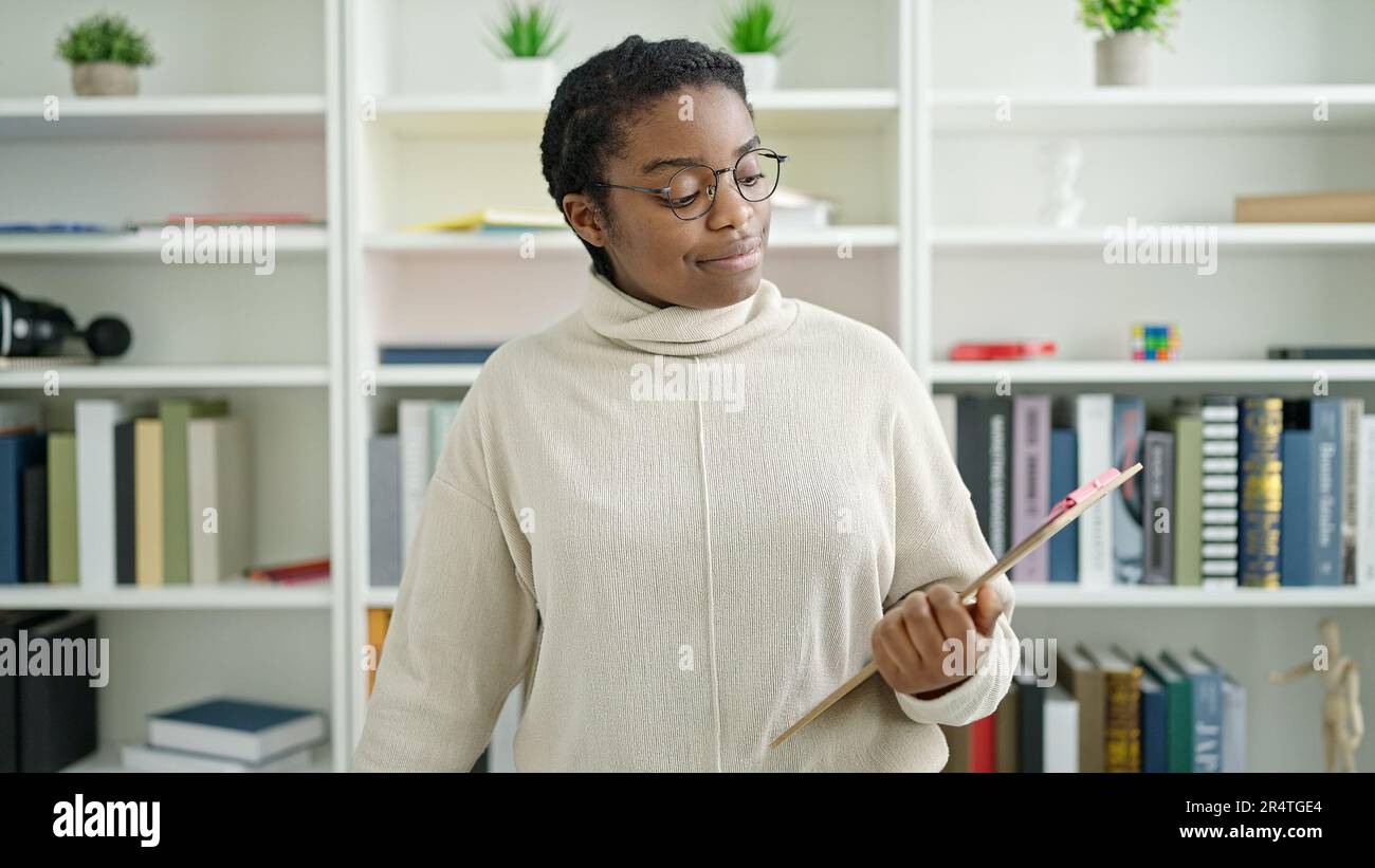 African american woman student reading document at library university ...
