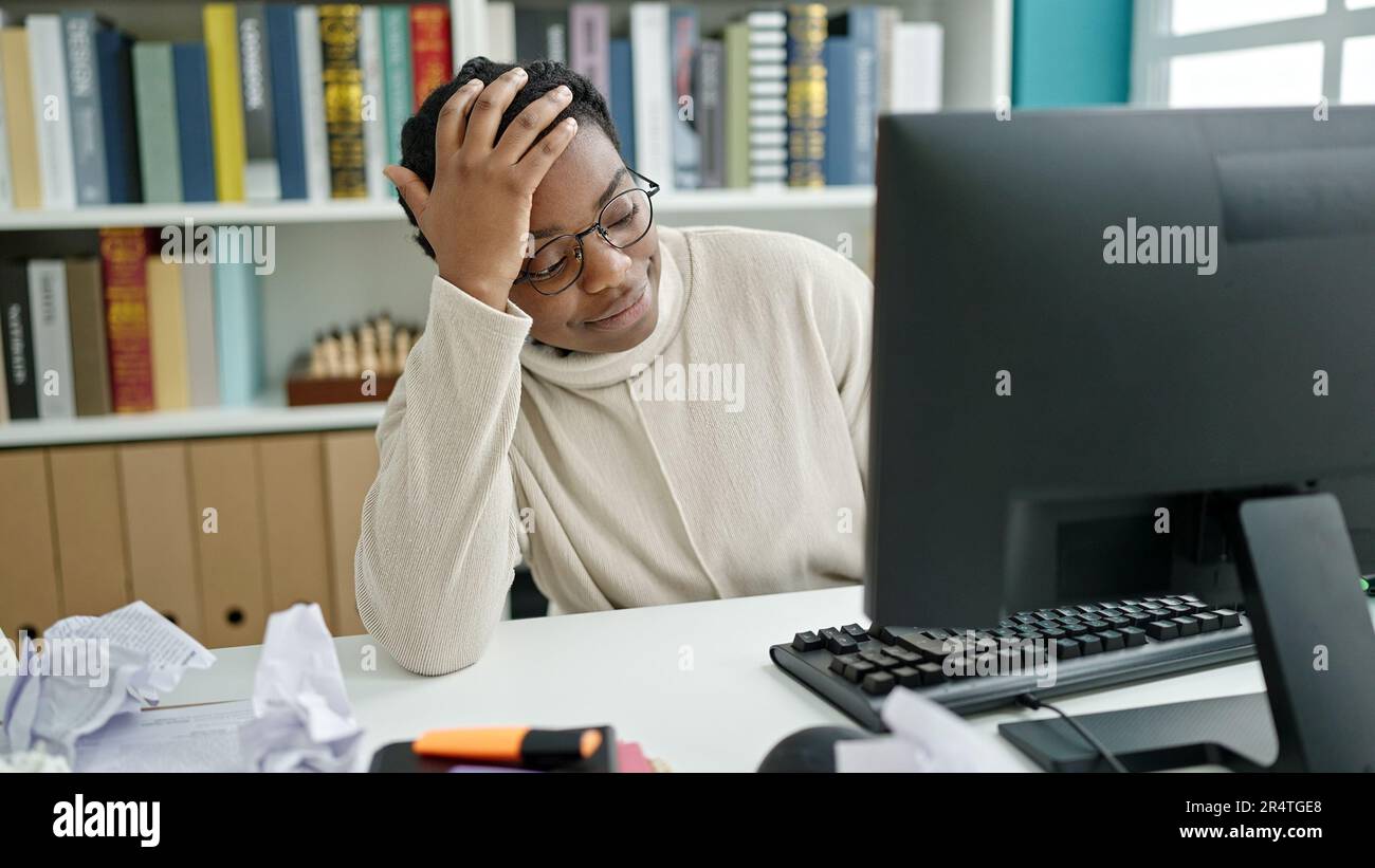 African american woman student using computer stressed at library ...